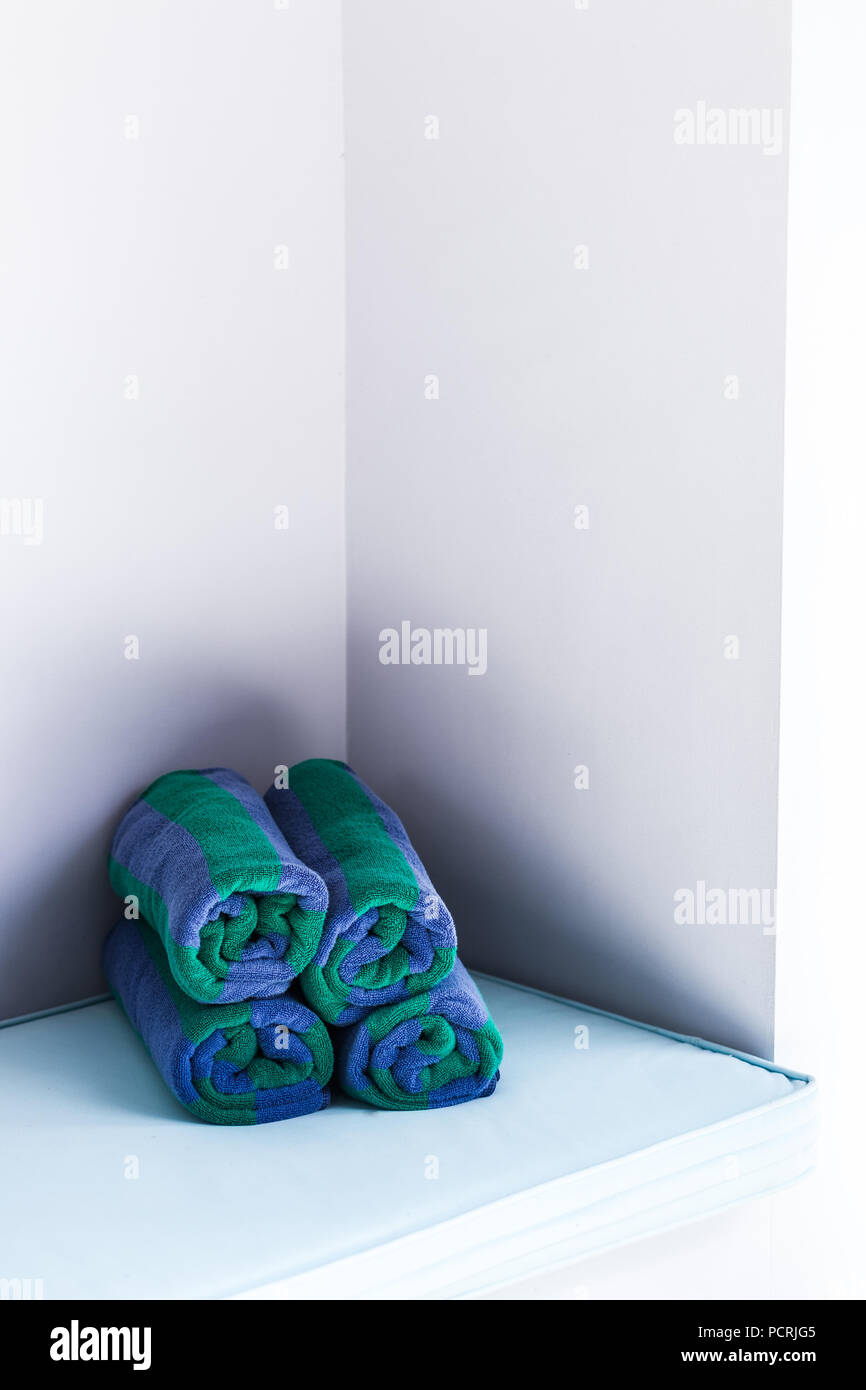 Rolled multicolor pool towels near white wall Stock Photo - Alamy