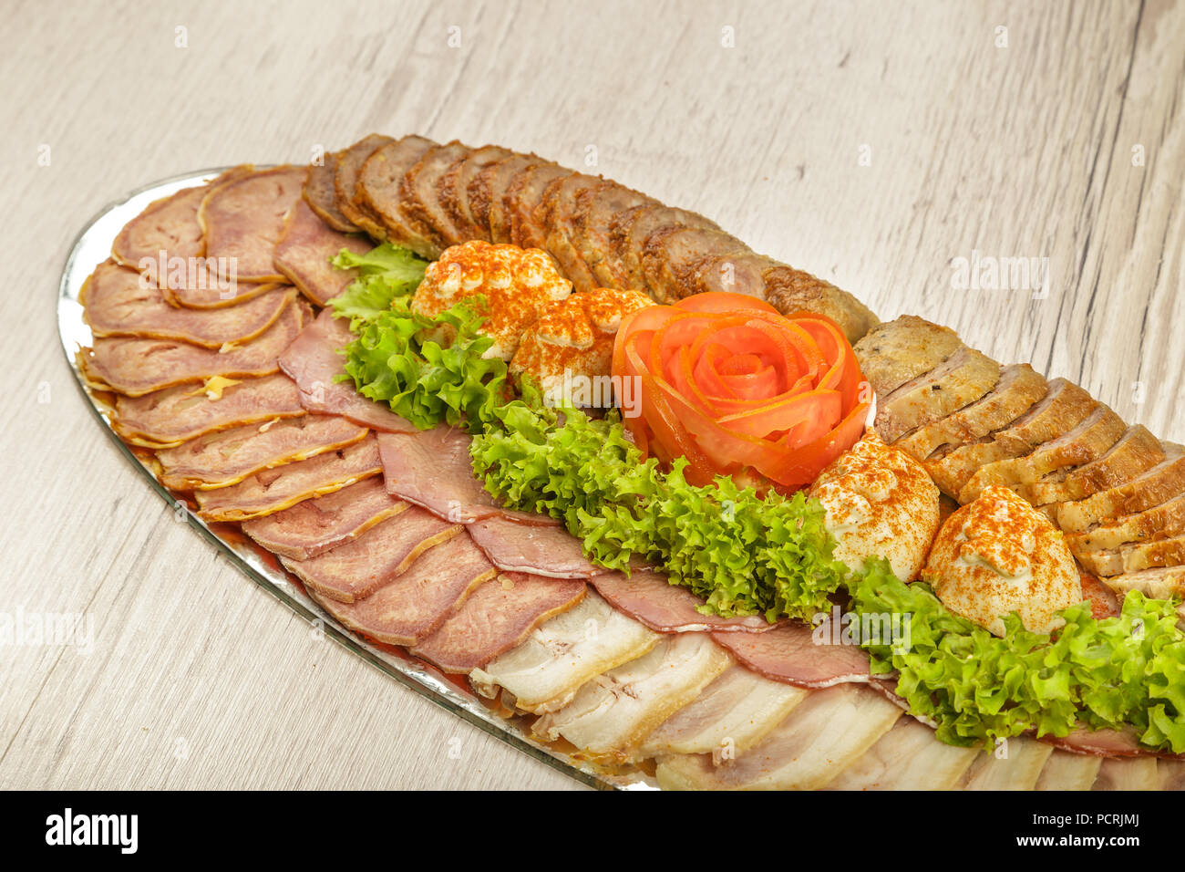 Meat sliced on a mirror dish decorated with verdure Stock Photo - Alamy