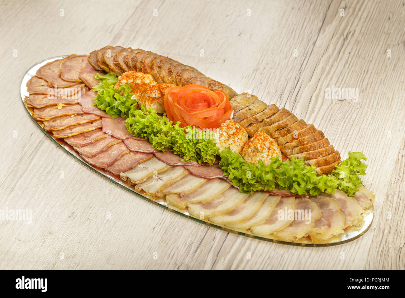 Meat sliced on a mirror dish decorated with verdure Stock Photo - Alamy