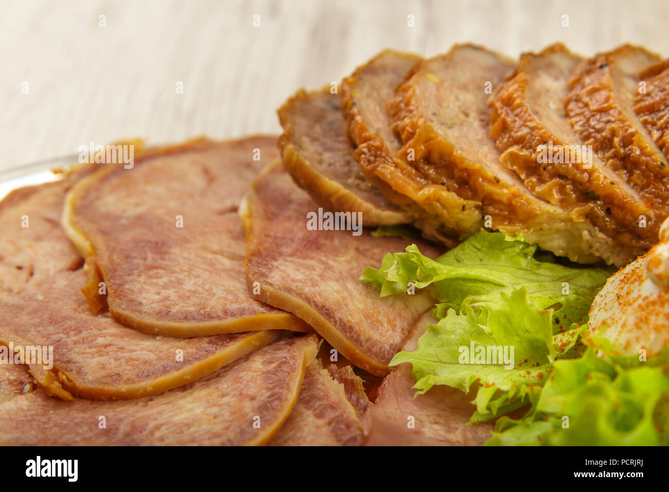 Meat sliced on a mirror dish decorated with verdure Stock Photo - Alamy