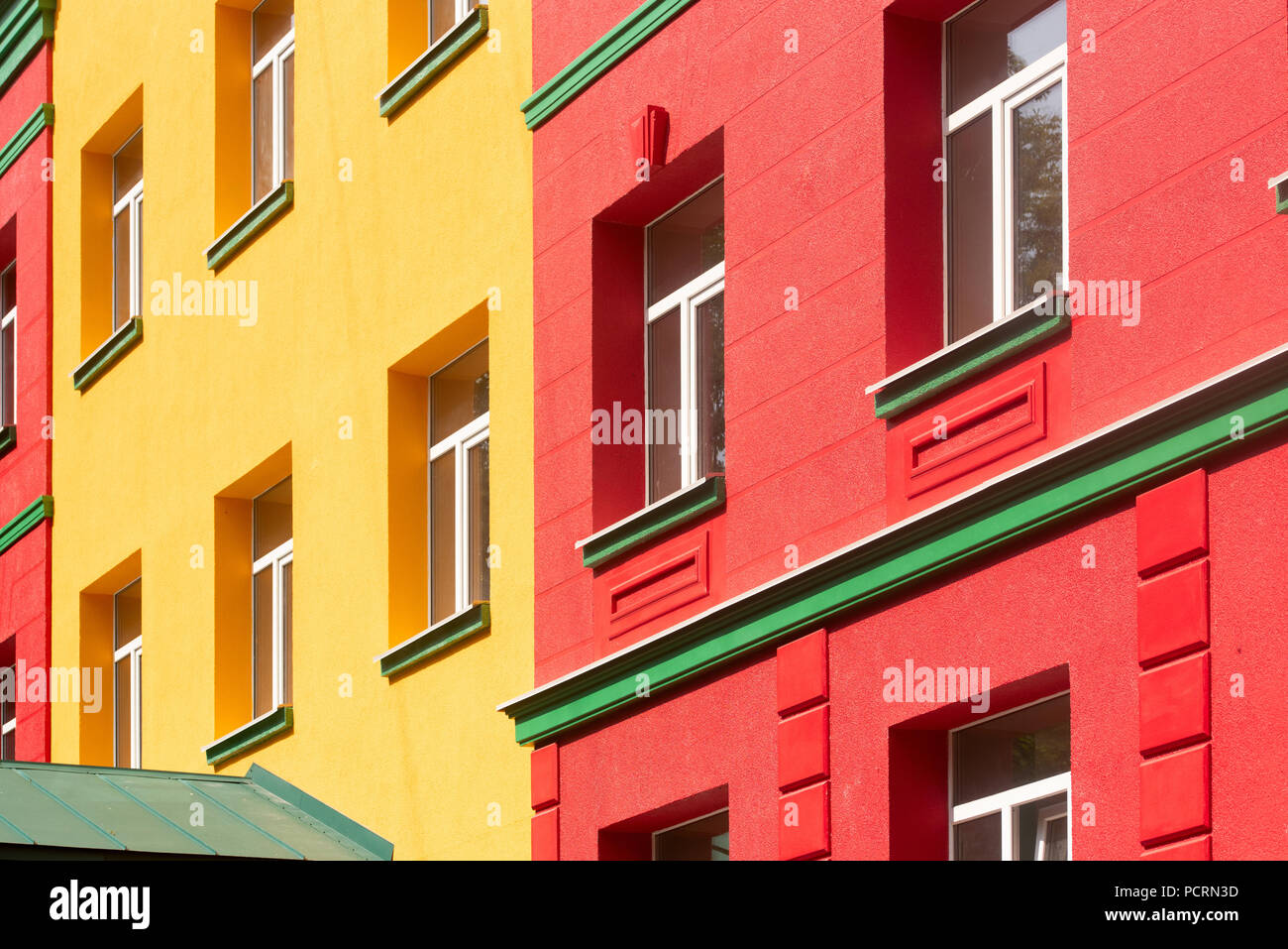 brightly colored building in burgundy and yellow with green cornice ...