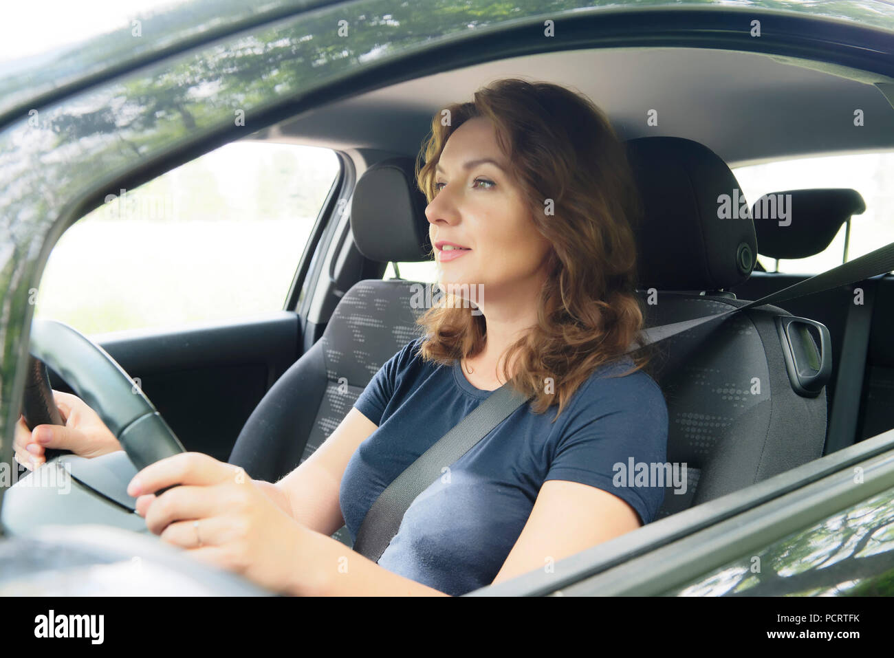 Woman driving her new car and looking outside Stock Photo - Alamy