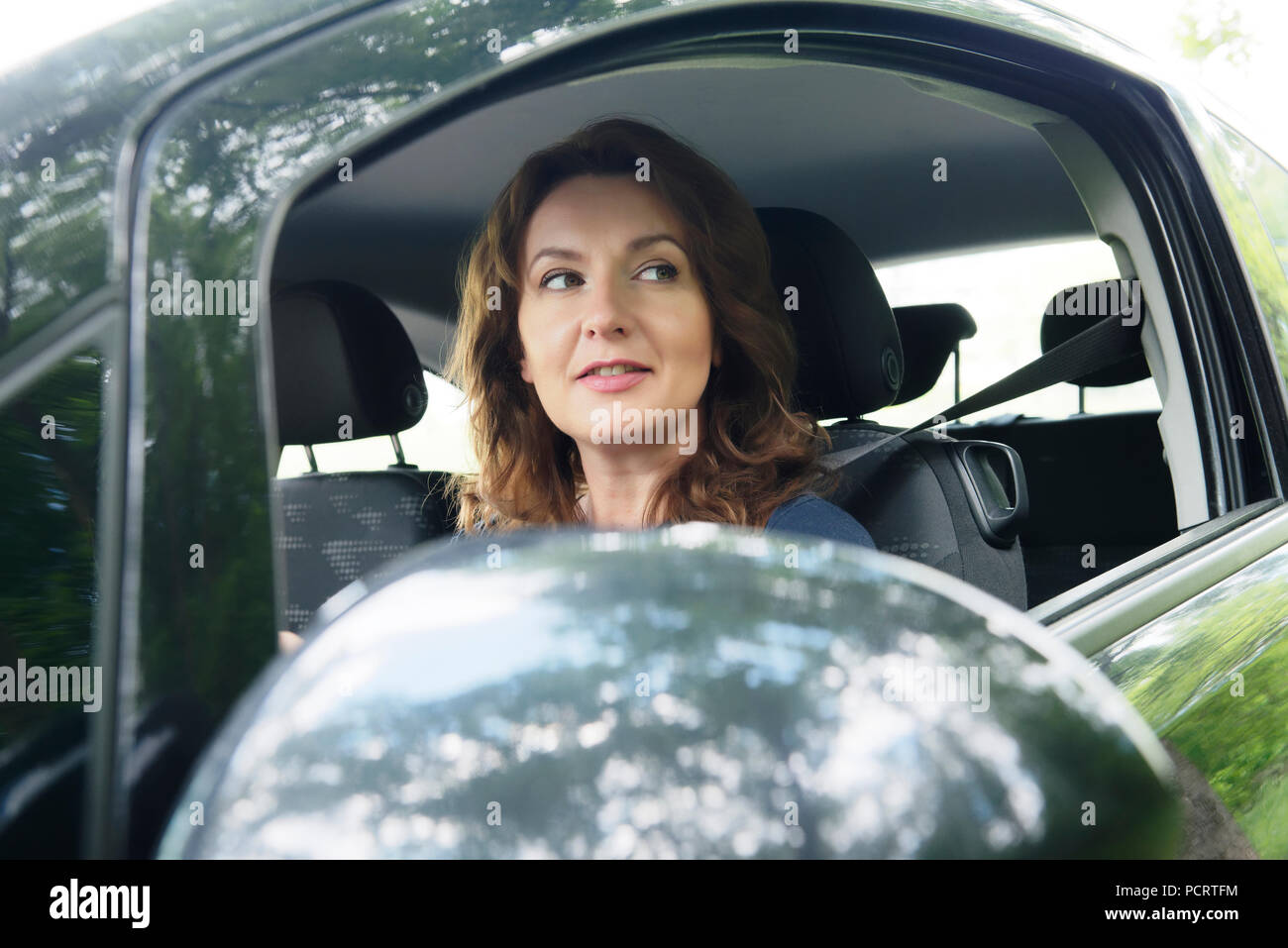 Woman driving her new car and looking outside Stock Photo - Alamy