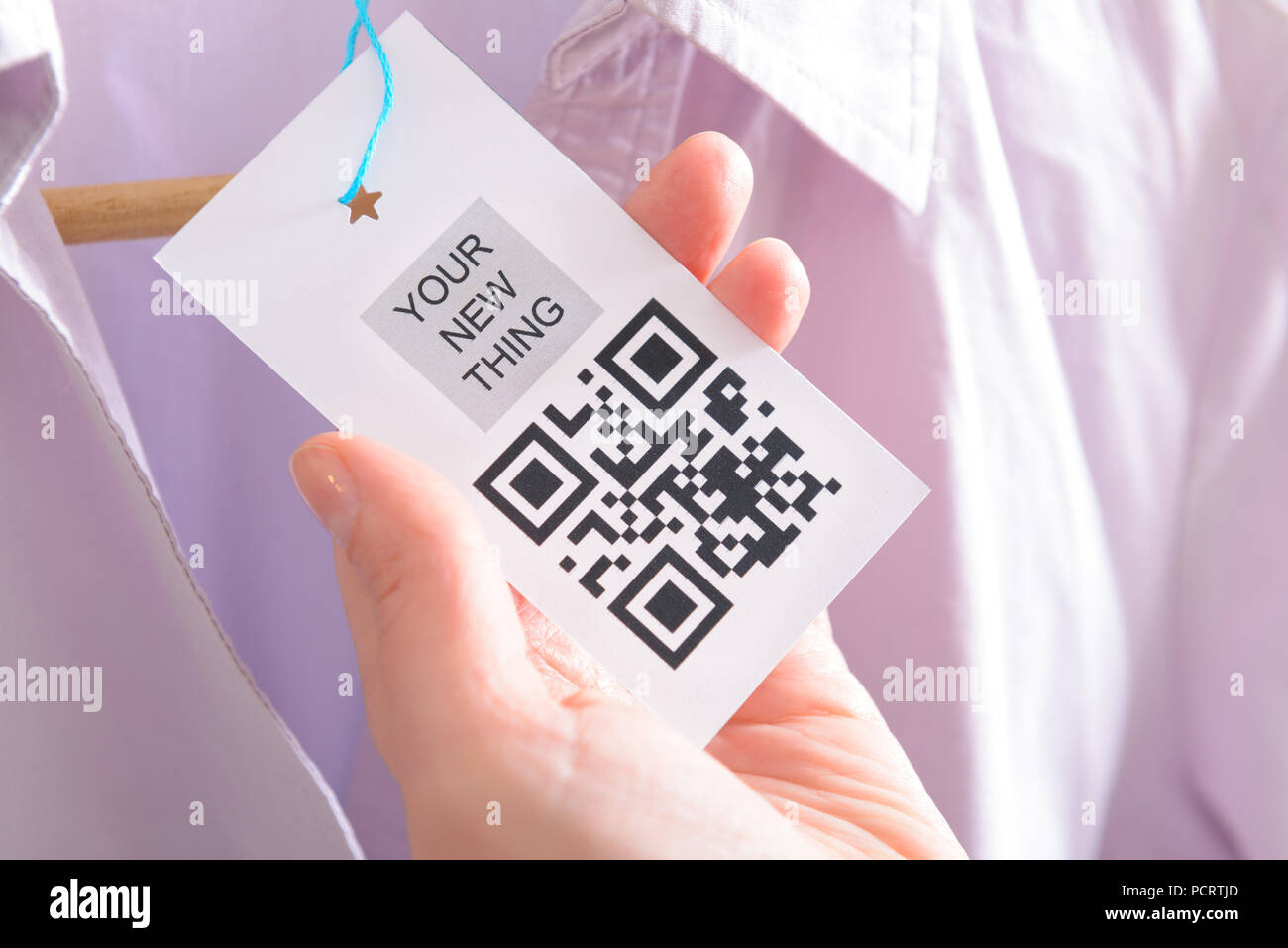 Woman's hand with a cloth label with QR code in a shop Stock Photo - Alamy