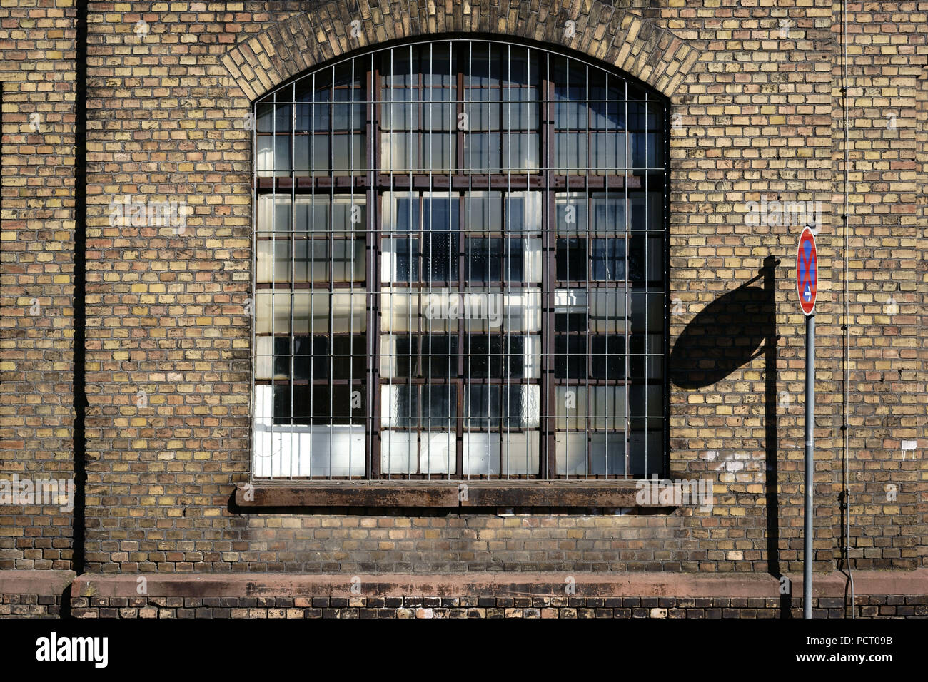 A stop sign casts a shadow on the brick wall on the disused industrial ...
