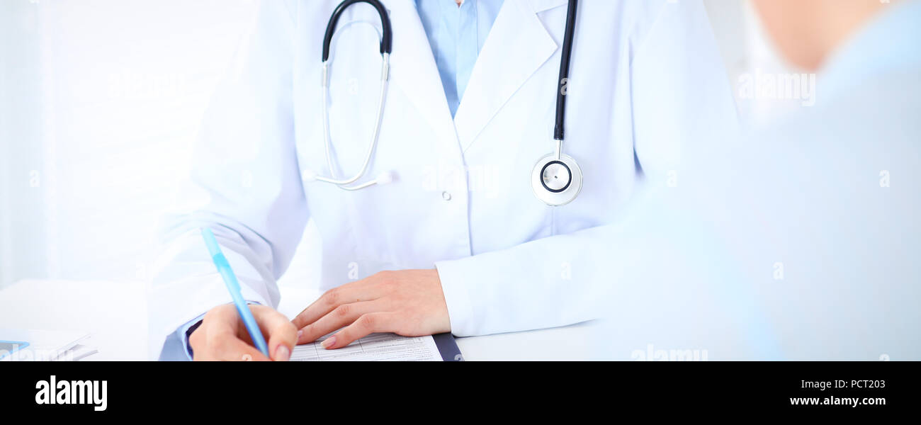Unknown female doctor and patient discussing something while sitting at ...