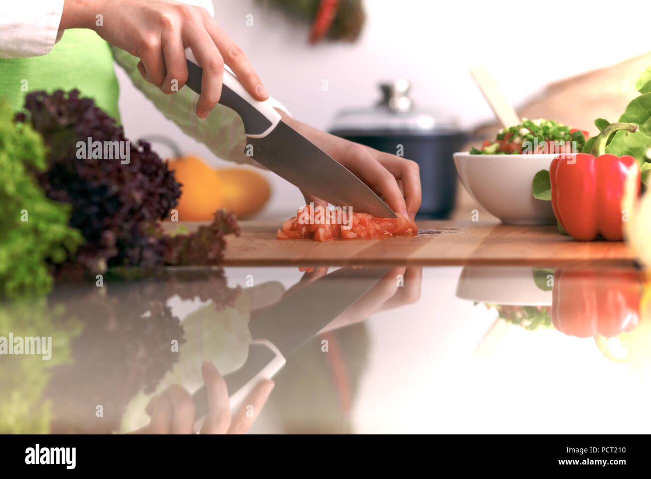 Close Up of human hands cooking vegetable salad in kitchen on the glass ...
