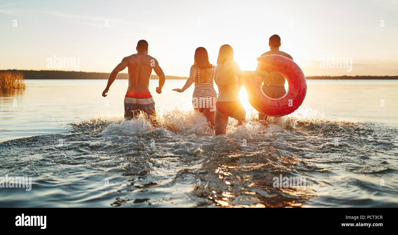 Rearview of a group of diverse young friends in swimsuits splashing ...