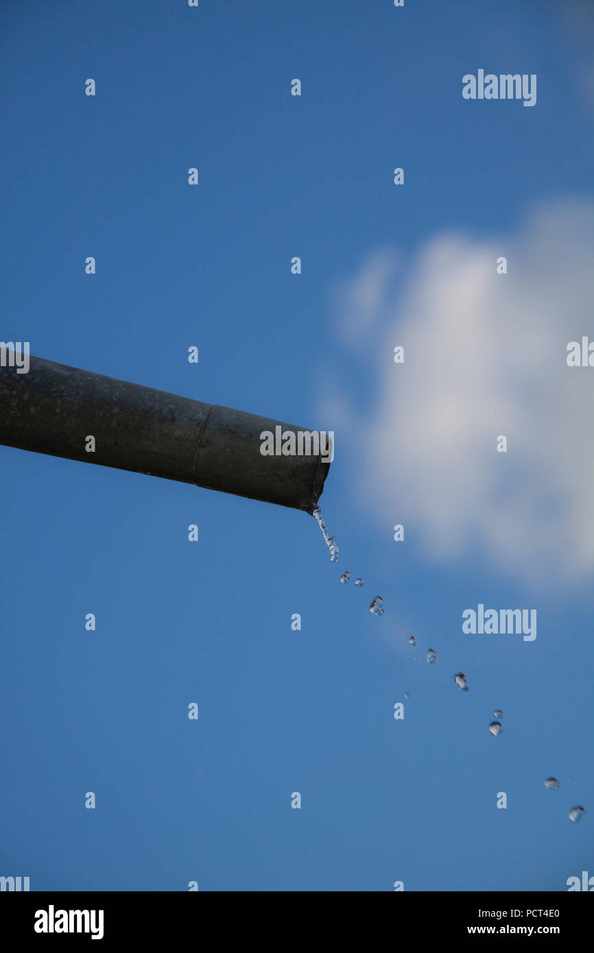 Drops of water flowing from pipe - close up with blue sky. Concept for ...