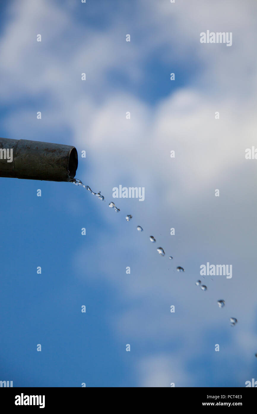 Drops of water flowing from pipe - close up with blue sky. Concept for ...