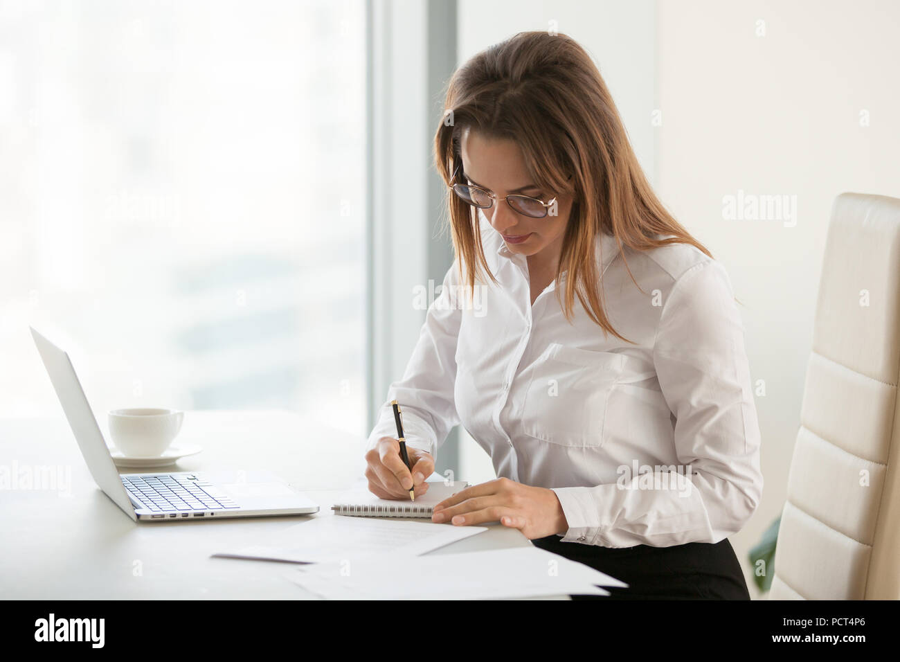 Serious businesswoman taking notes during routine office morning Stock ...