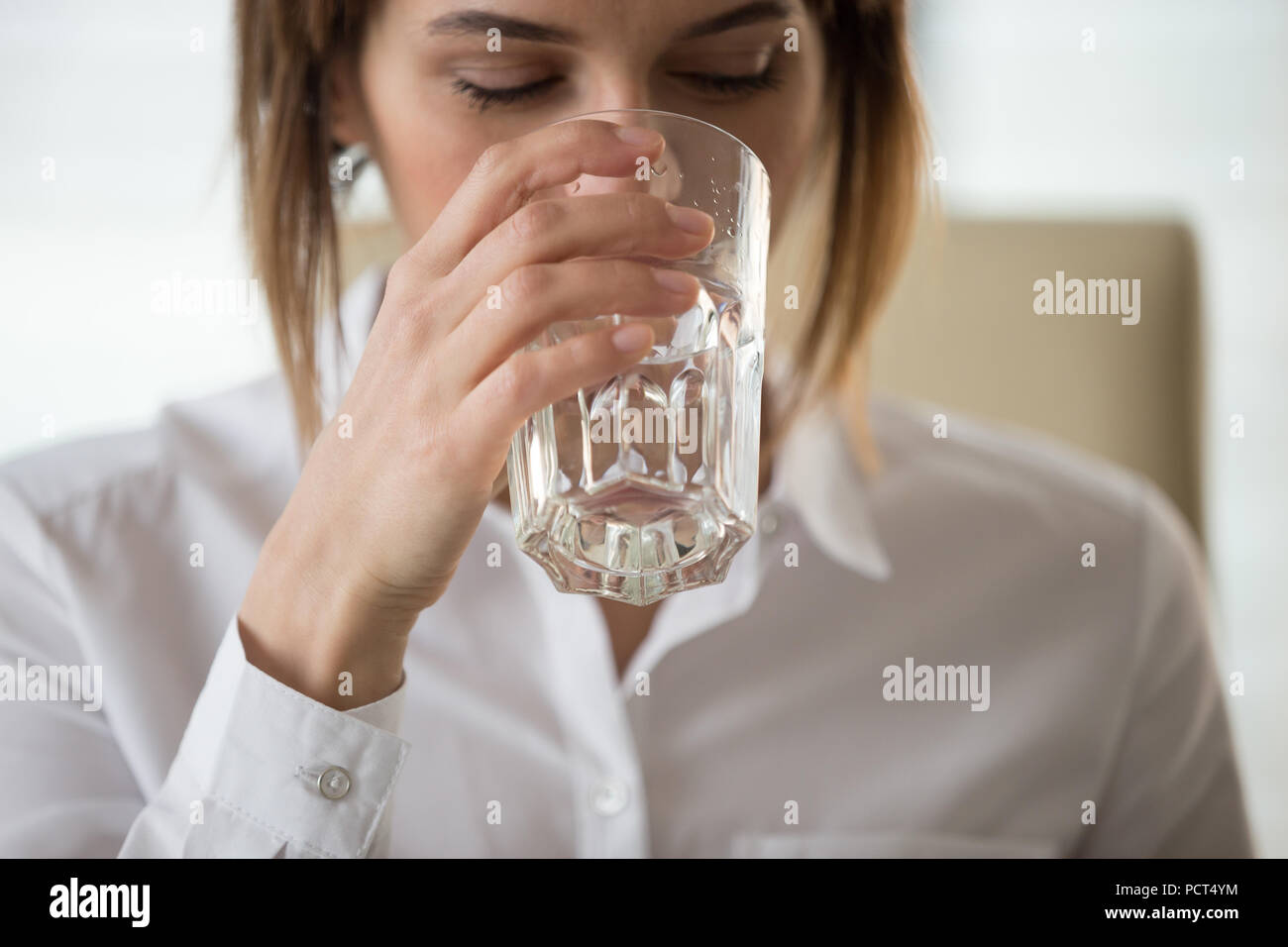 Dehydrated female office worker drinking still mineral water Stock ...