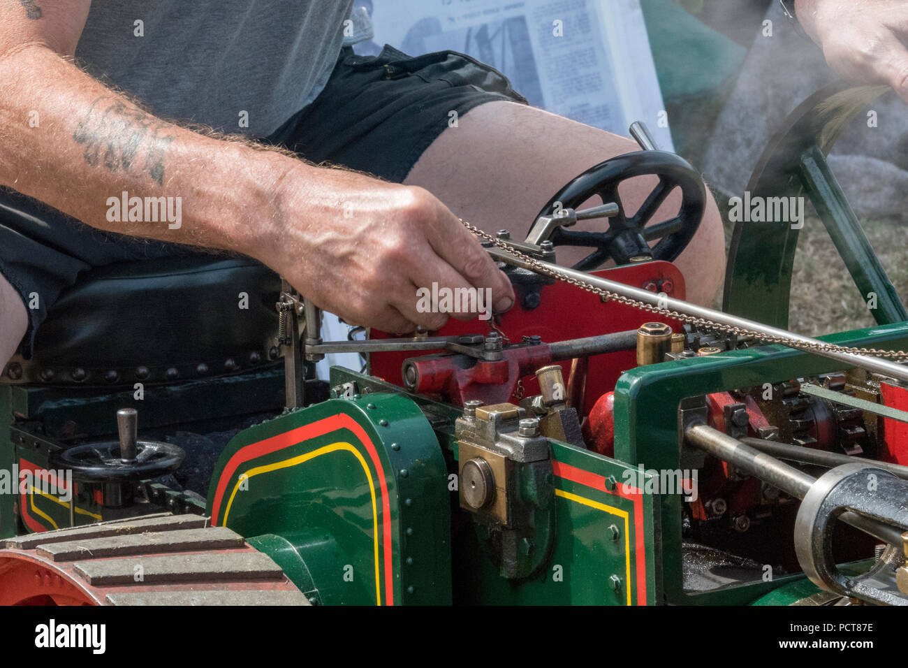 man riding on a miniature steam engine model at a steam rally or model ...