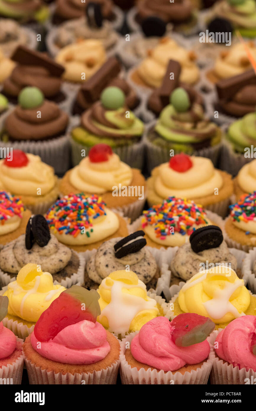 small cupcakes in bright colours on an artisan bakers or bakery stall ...