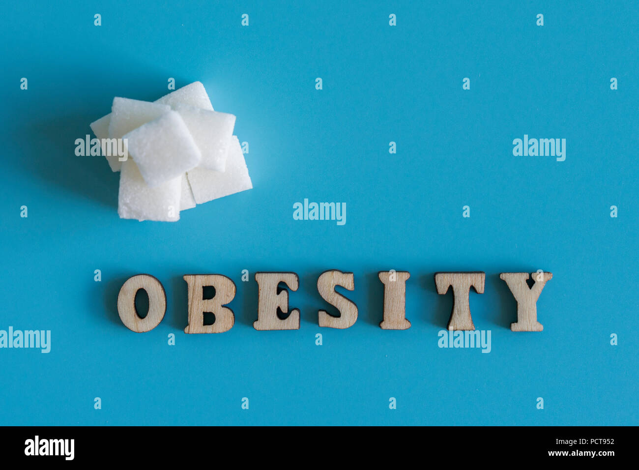 inscription obesity on a blue background. The concept of obesity from ...