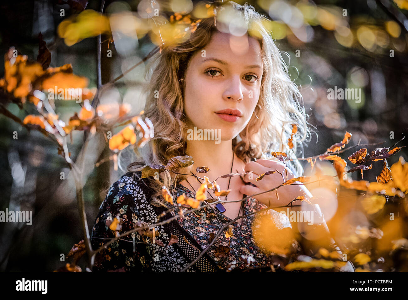 young woman with blond hair in the forest, serious and thoughtful look ...