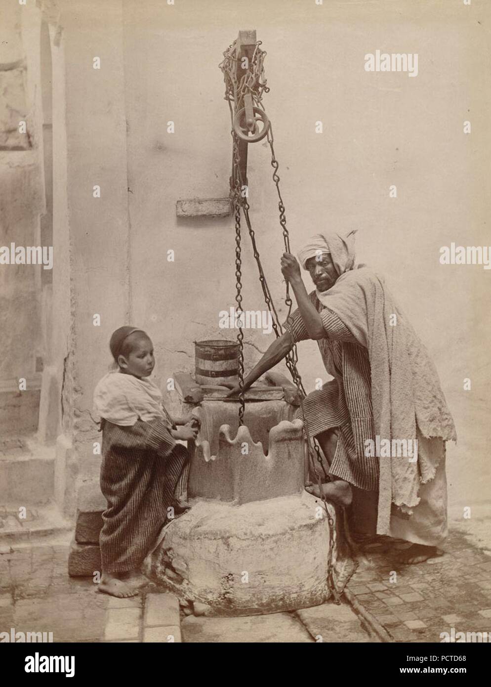Algerian man and boy drawing water from a well (circa 1892 Stock Photo ...