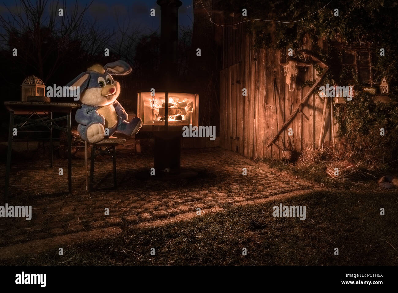 Large stuffed bunny on beer bench beside a fire pit in the garden of a ...