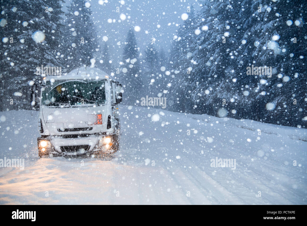 Delivery of LPG gas in winter on mountain road under heavy snowfall ...
