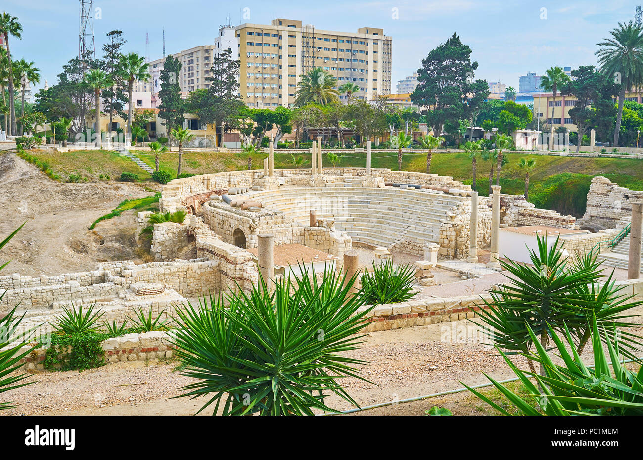 The antique amphitheatre of Roman period is surrounded by green palms ...