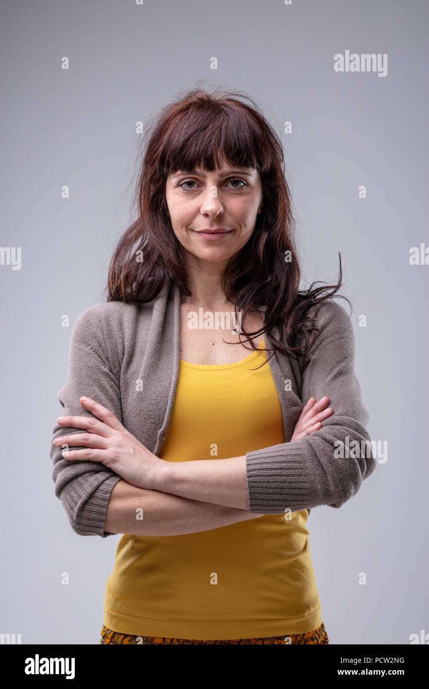Serious determined attractive woman with long brown hair and folded ...