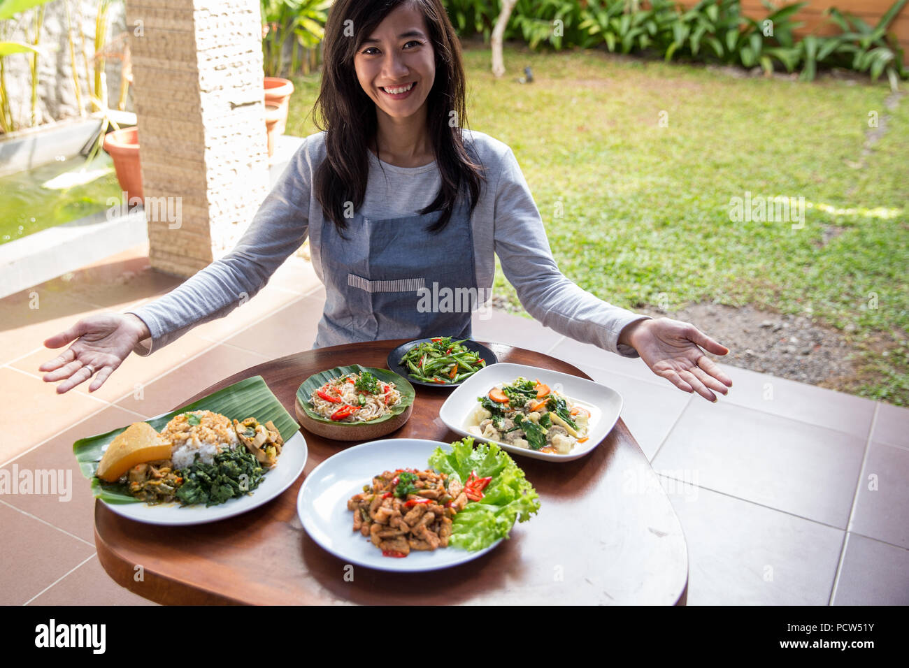 beautiful asian woman presenting various indonesian food on a table ...