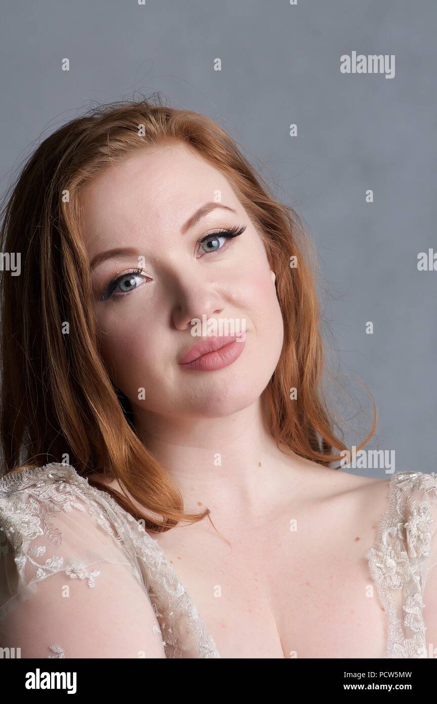 Headshot of a red haired girl in the studio wearing a lacy cape. She ...