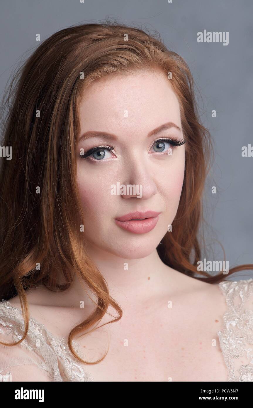 Headshot of a red haired girl in the studio wearing a lacy cape. She ...