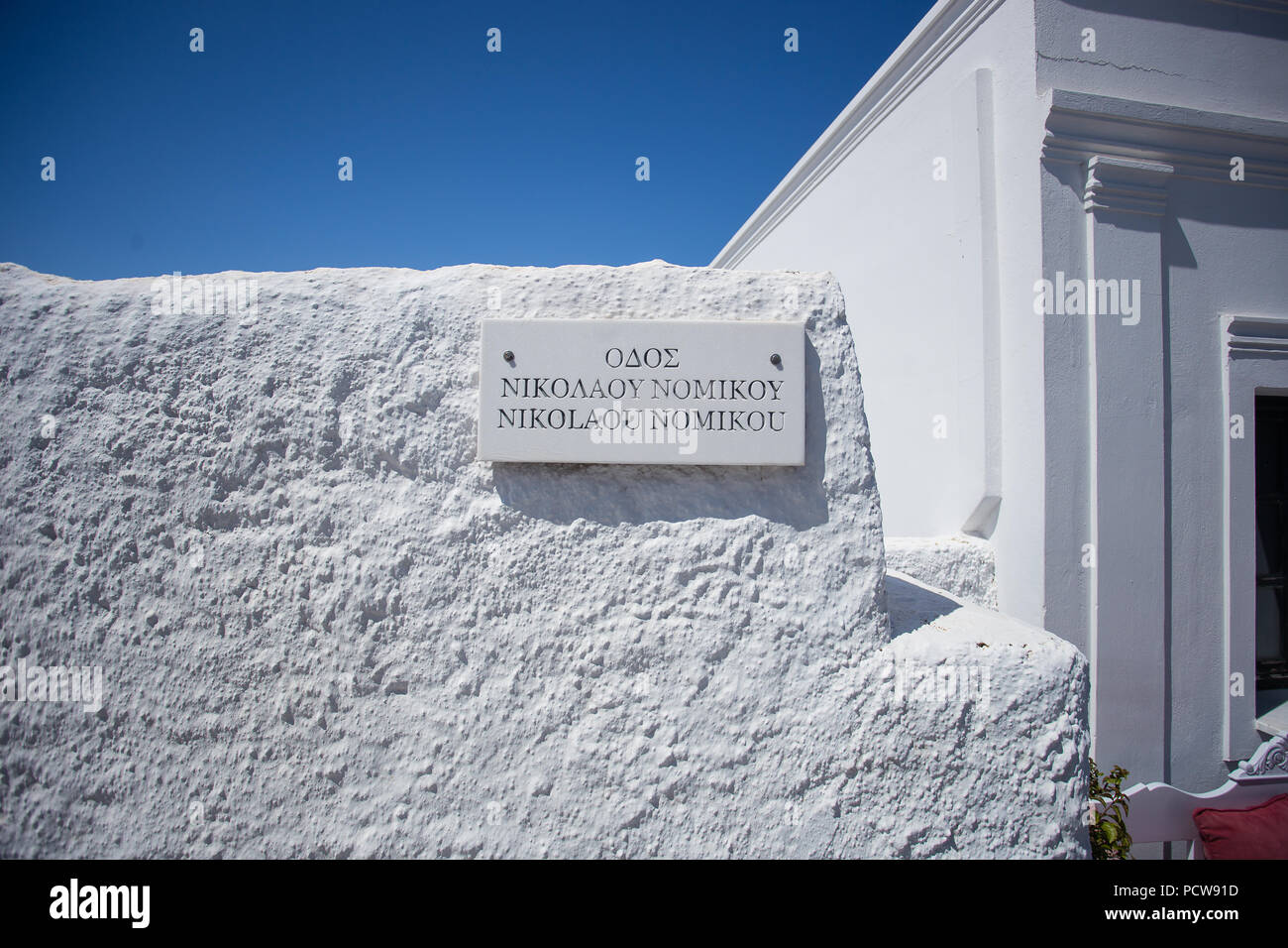 marble sign in greek, in traditional white washed wall bathed by light ...