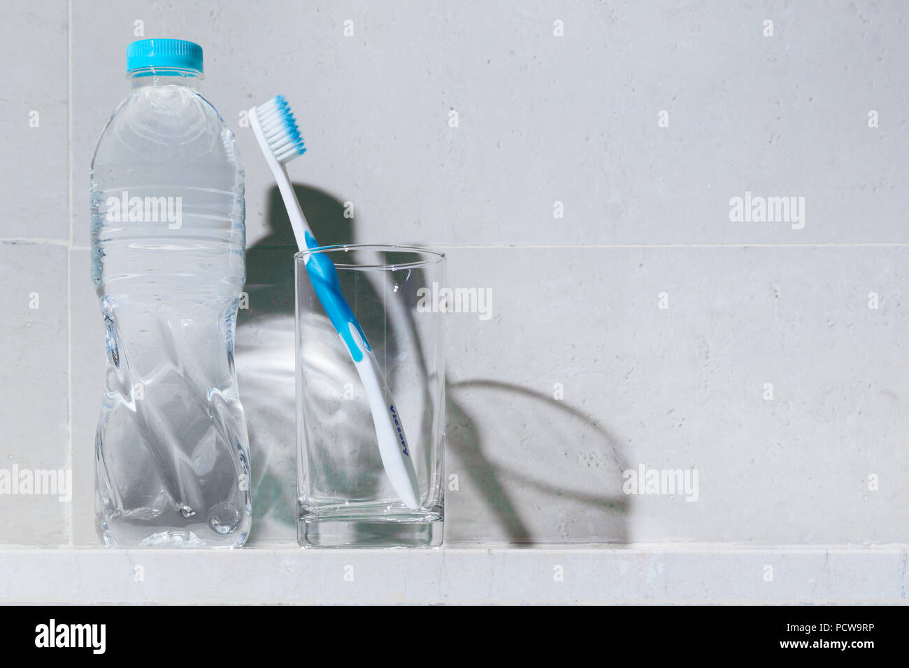 Clean white toothbrush with blue trim in clear drinking glass and a ...