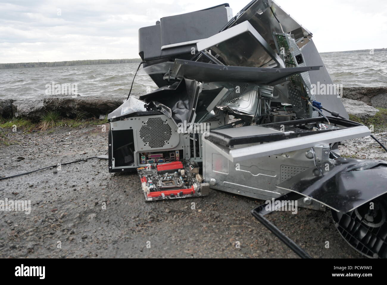 Broken computer parts, monitors and printers in front of nature ...