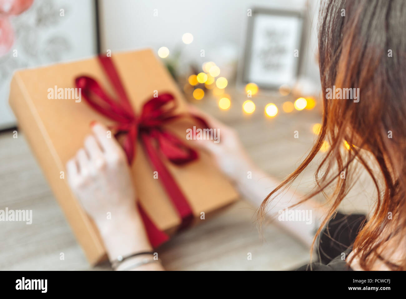 Woman wrapping present in paper with red ribbon Stock Photo - Alamy