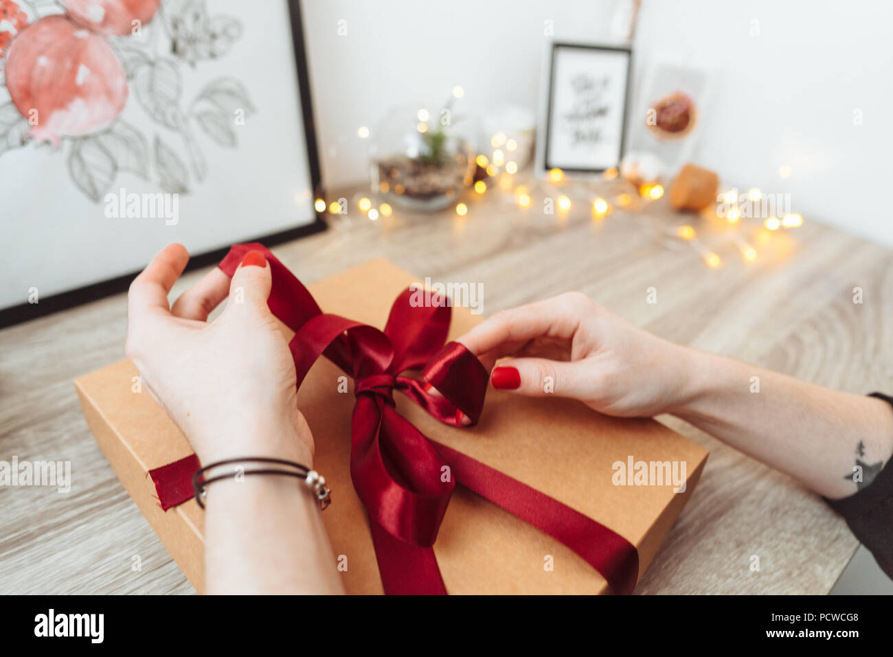 Woman wrapping present in paper with red ribbon Stock Photo - Alamy