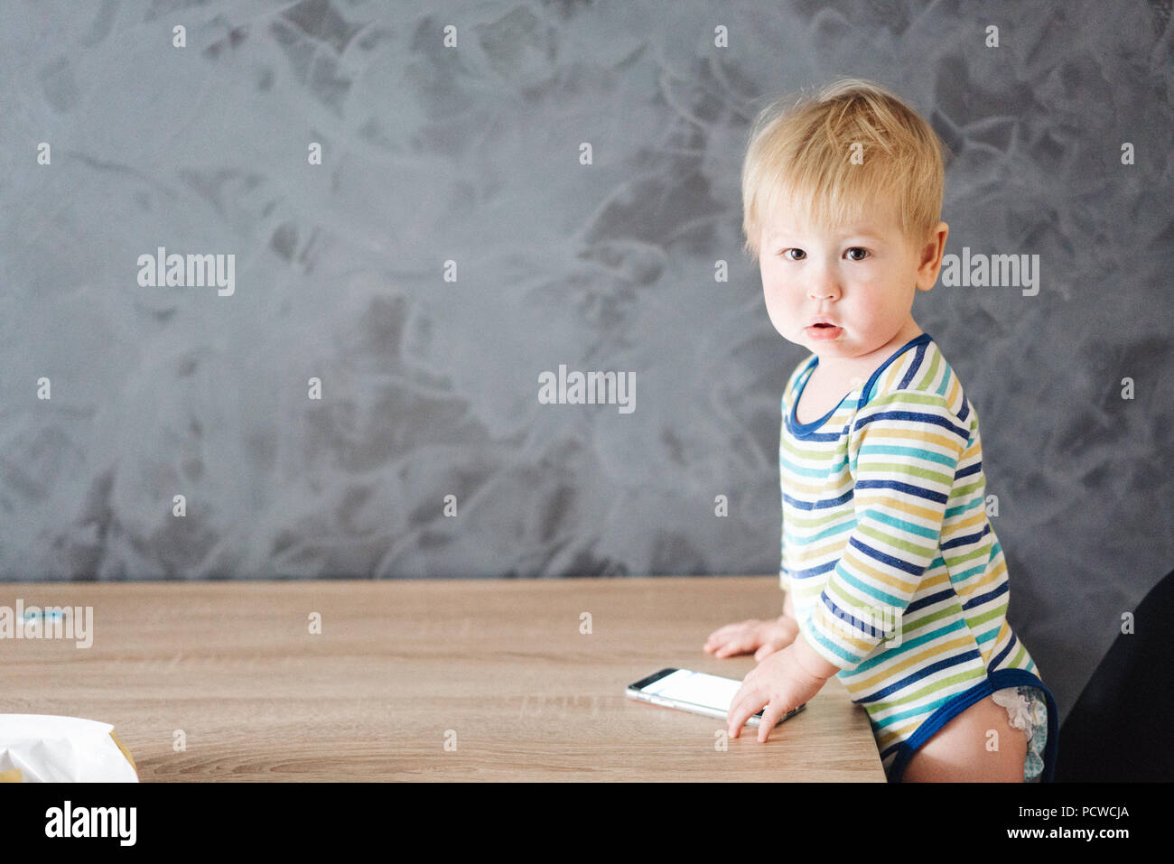 baby boy standing near the table Stock Photo - Alamy