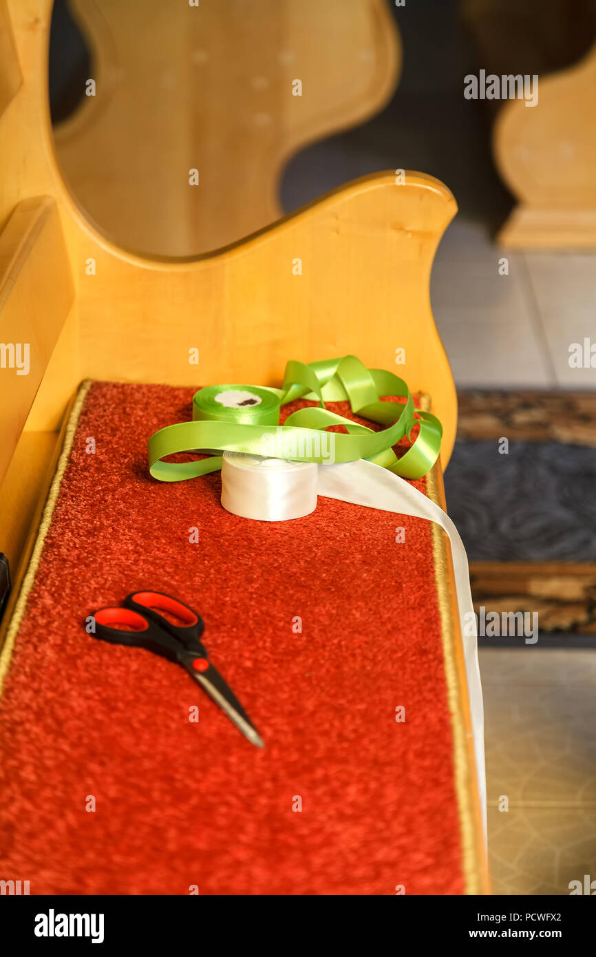 Decorative colored ribbons and scissors lie on a bench with a velvet ...