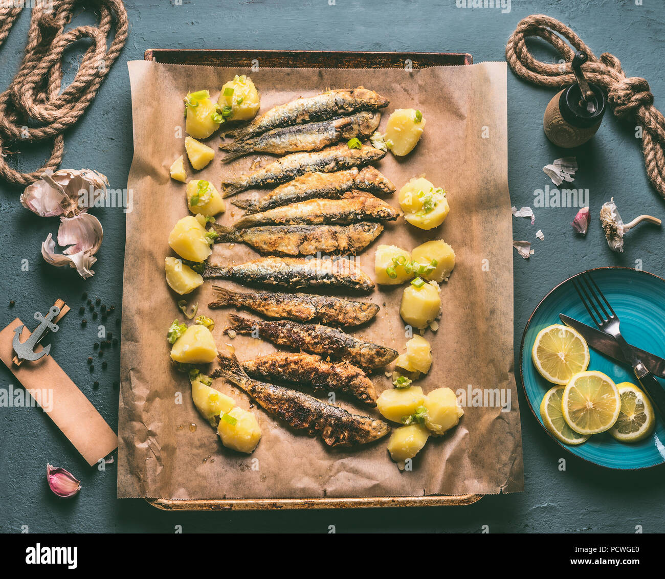 Grilled sardines with potatoes on baking tray with ingredients: lemon ...