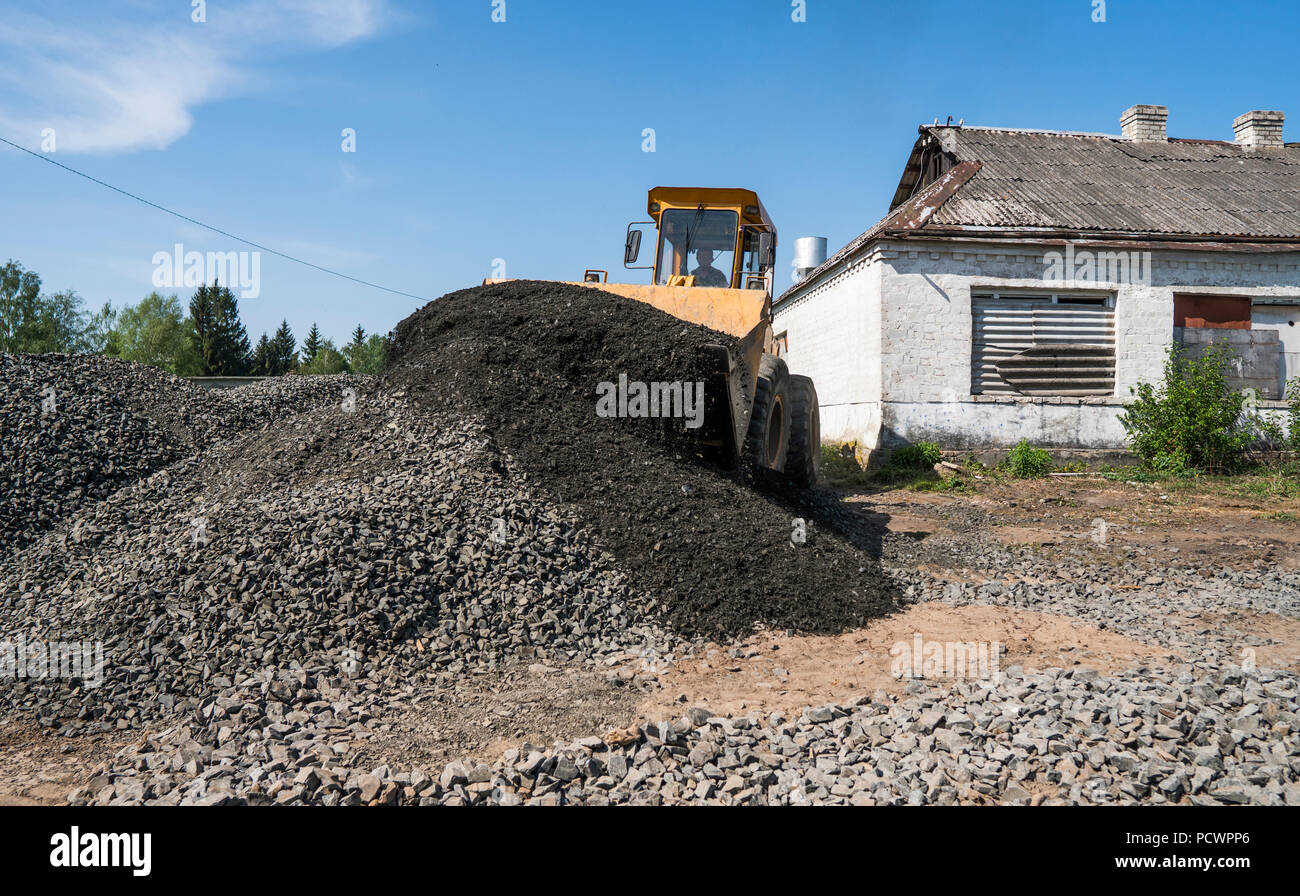 Yellow loader moving with uploaded bucket to the truck with stone ...
