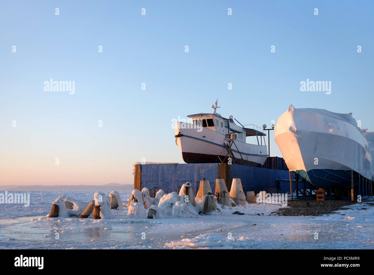 Boats covered for winter in the ice Stock Photo - Alamy