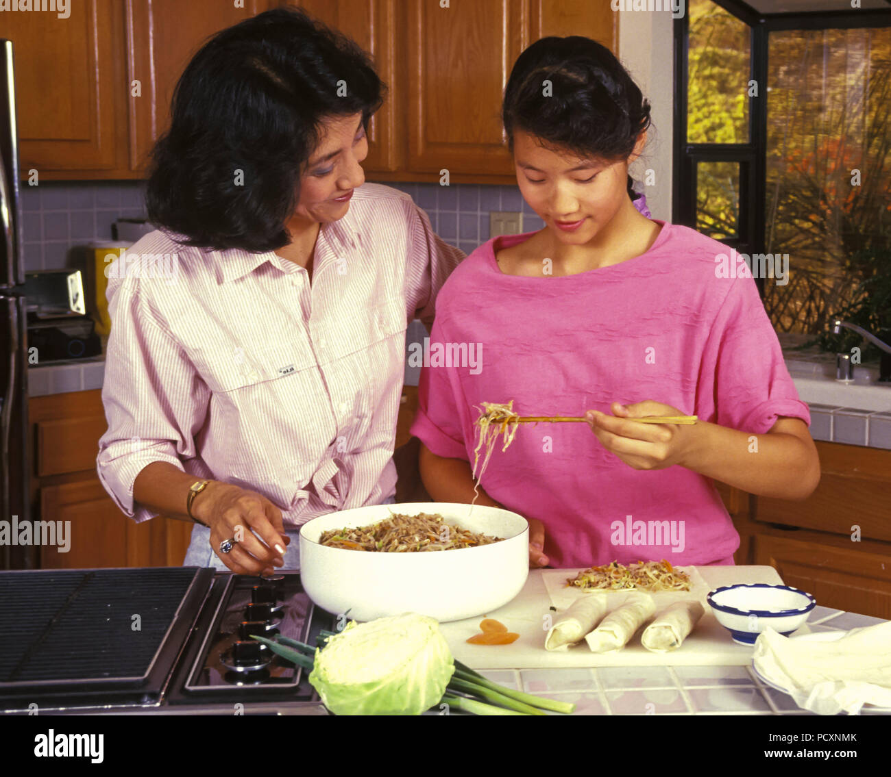 Chinese mother and daughter learning to make spring rolls © Myrleen ...