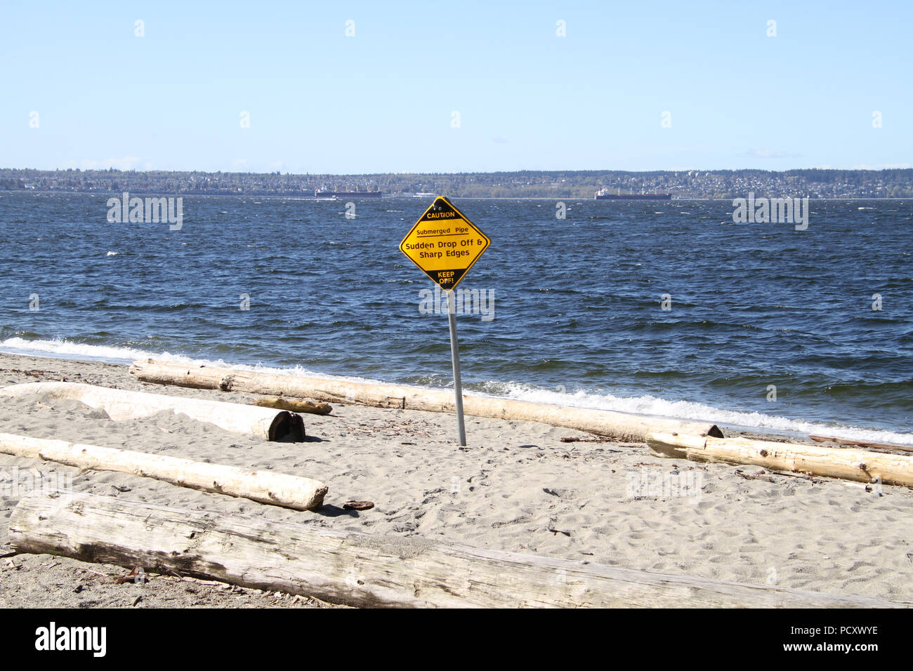 A yellow and black sign indicating a submerged pipe and a drop off with ...