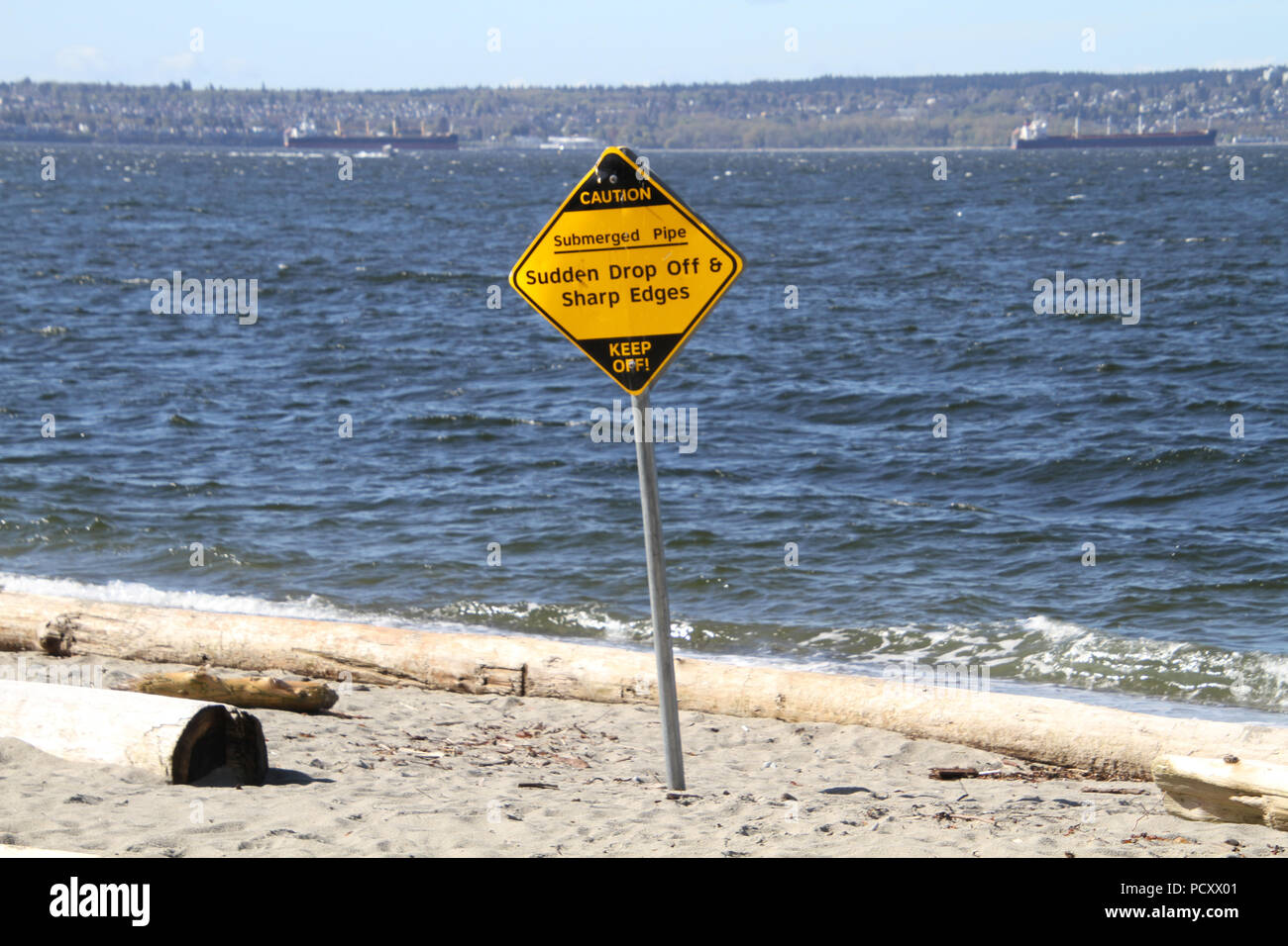 A yellow and black sign indicating a submerged pipe and a drop off with ...