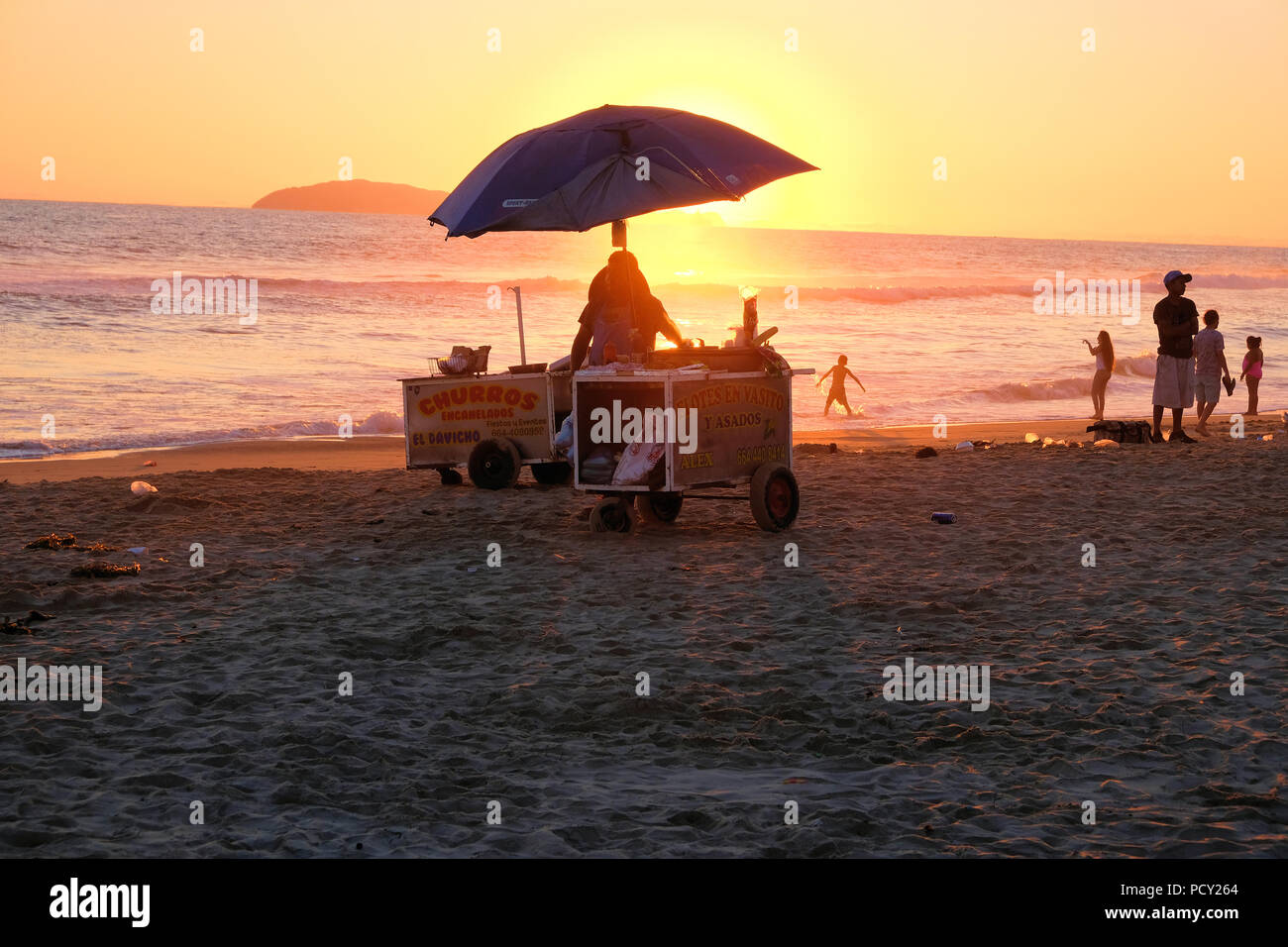Churro vendor with a setting sun on the beach in Rosarito, Baja ...