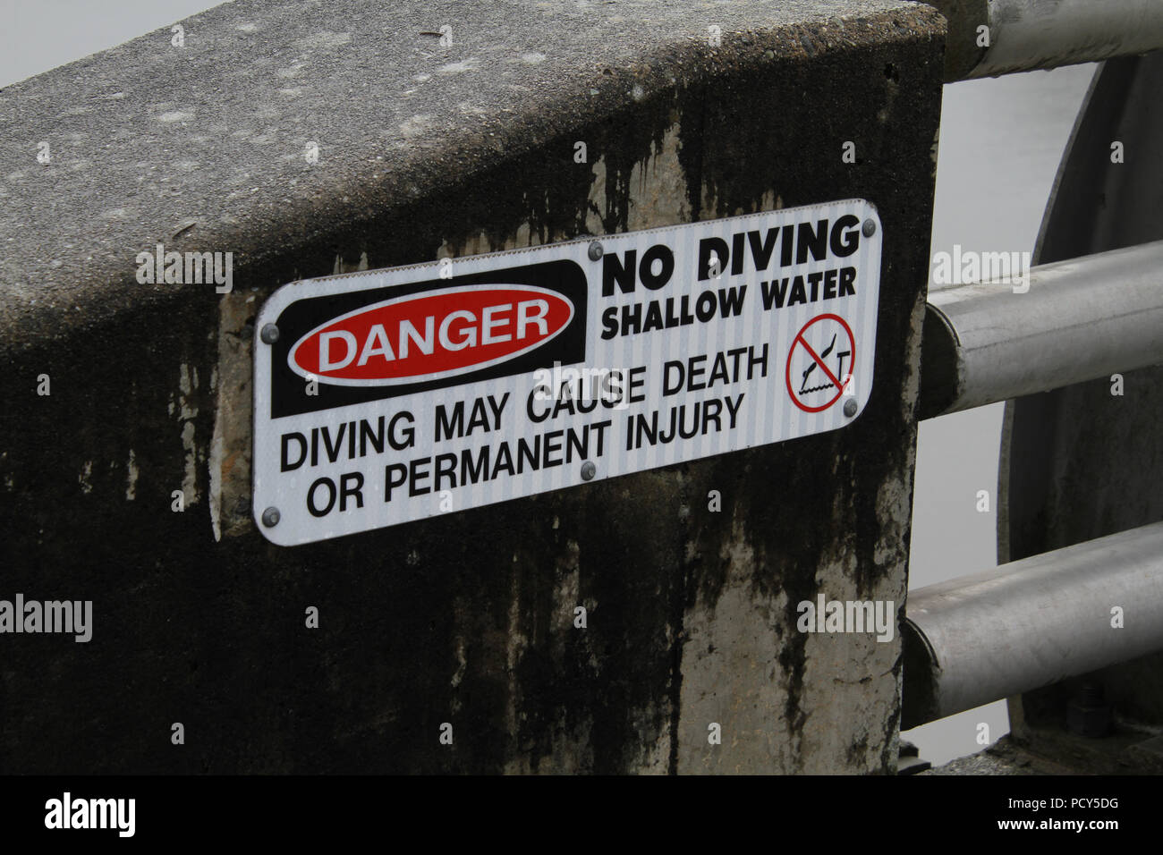 A close up of a danger no diving sign on a concrete wall next to a ...