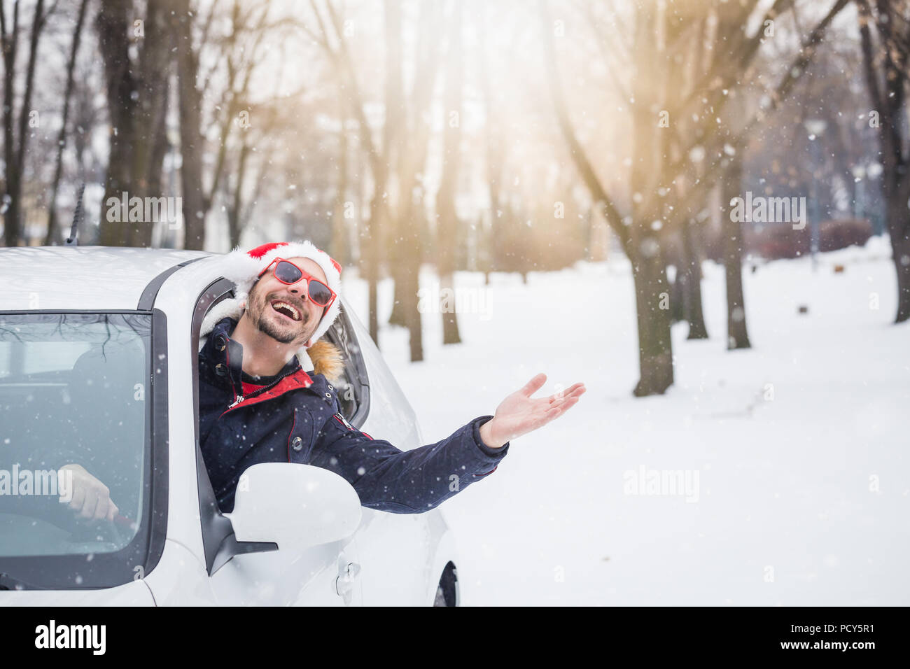 Portrait of car driver with santa hat through car window enjoying the ...