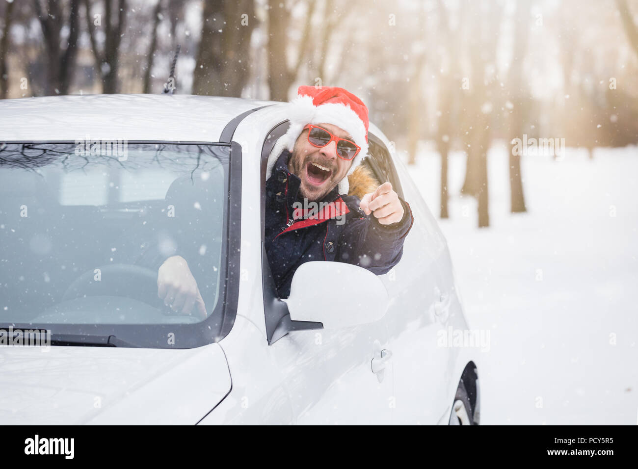 Portrait of car driver with santa hat through car window. On the road ...