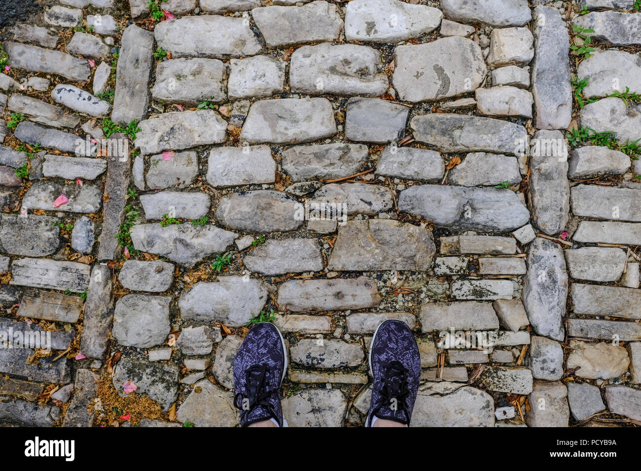 Pair of feet in shoes on an old cobbled path. Start of a new journey ...