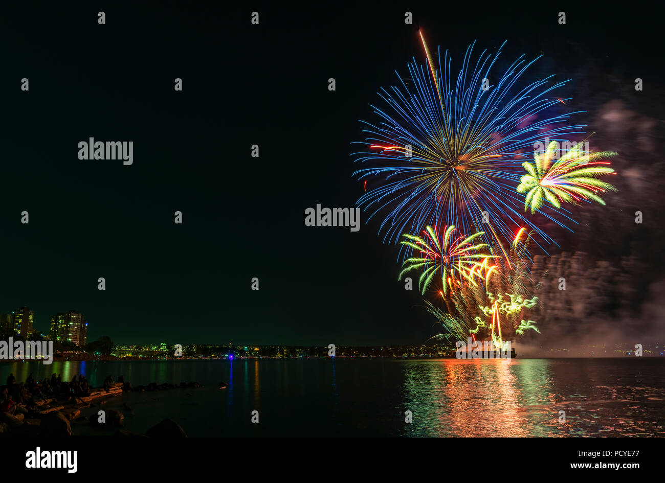 Multicolored fireworks over the ocean in the big city, silhouettes of ...