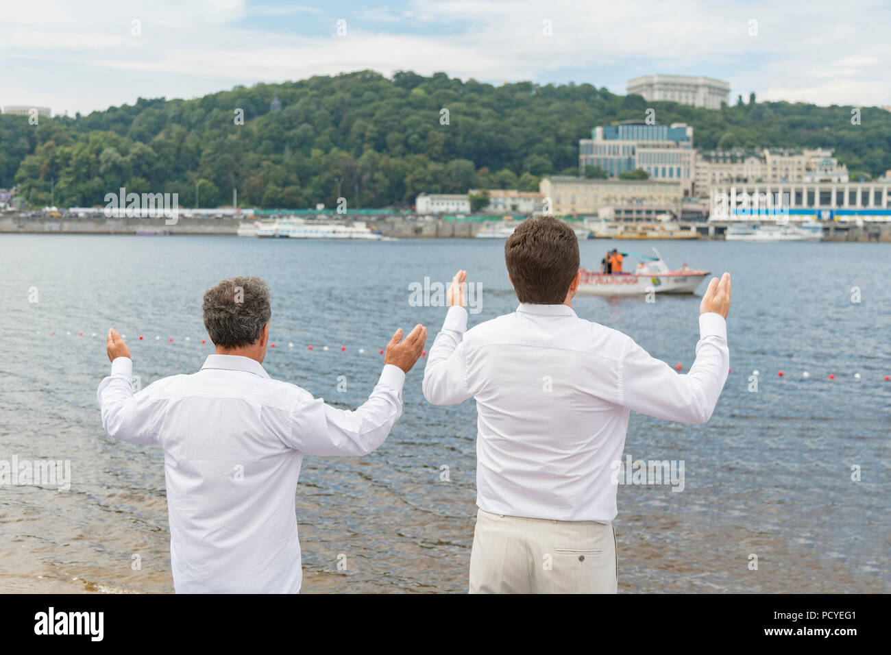 Two men praying. Two men in white clothes pray on the river bank Stock ...