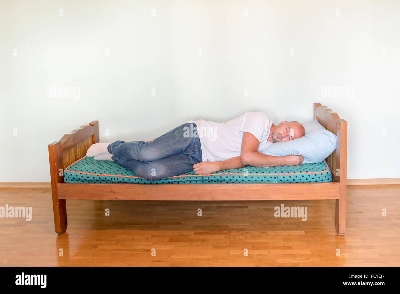 A man is sleeping on an empty bed in an empty room. The concept of ...