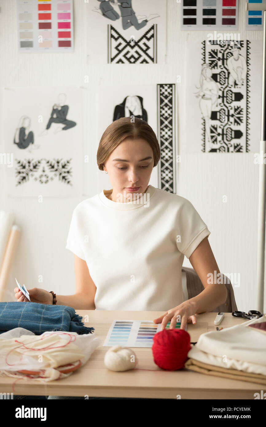 Serious female fashion designer choosing color swatch for new co Stock ...